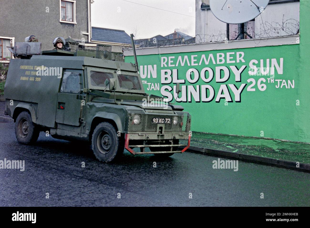 British soldiers patrol in an armored Land Rover past a mural marking ...