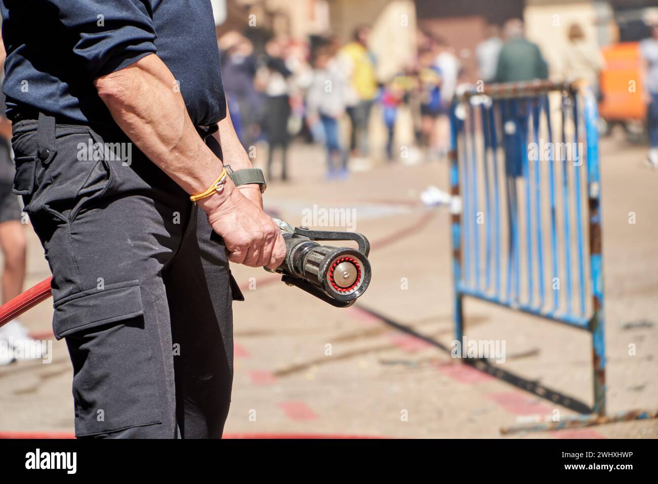 Fireman in with hose ready to put out a fire on the street at day time ...