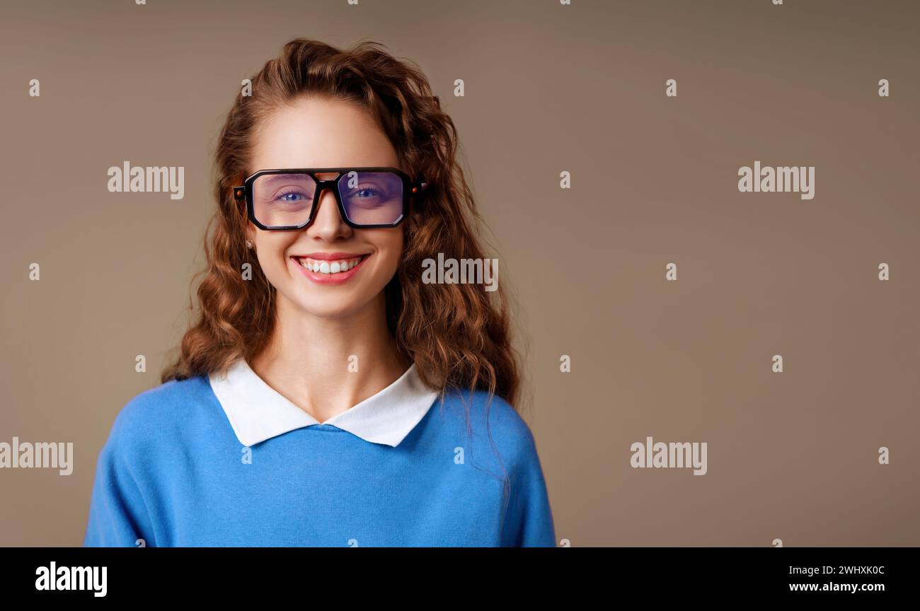 Young positive thinking smiling student in glasses portrait in blue ...