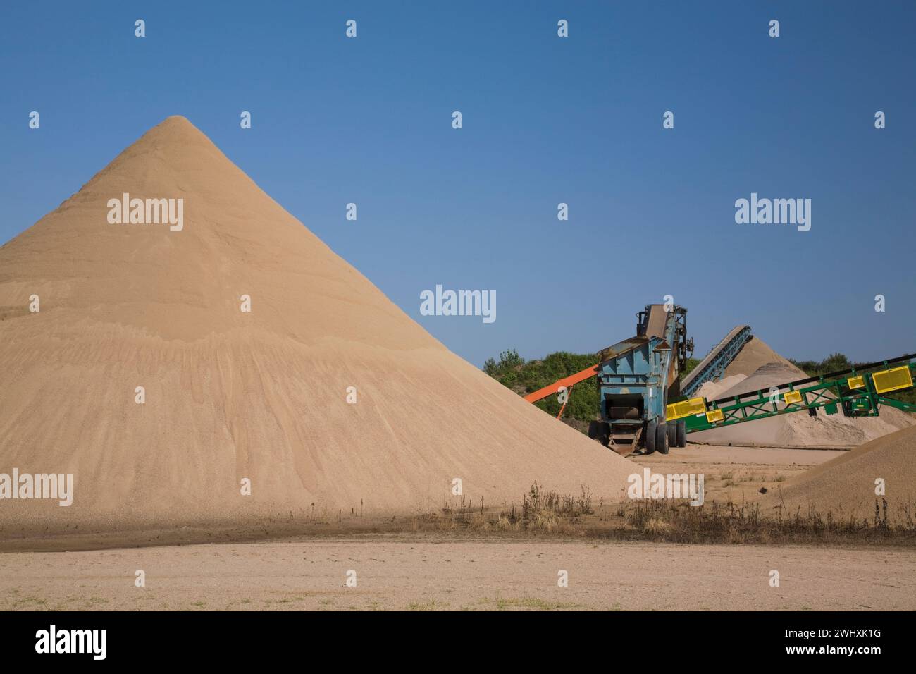Mounds of fine tan coloured sand and stacking conveyor belts in ...