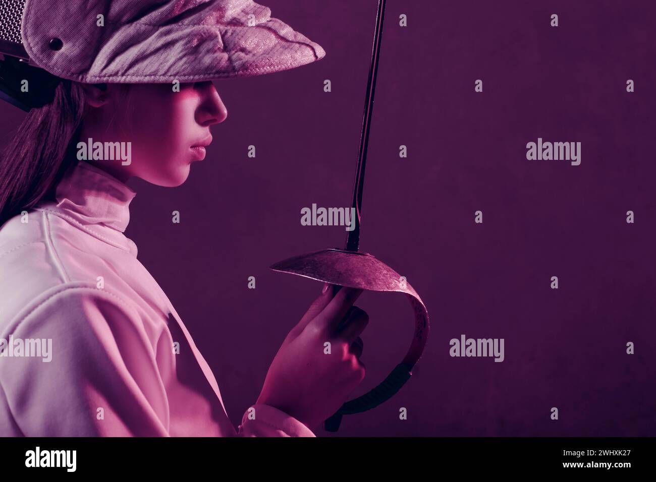 Young woman fencer profile portrait with fencing equipment and sword ...