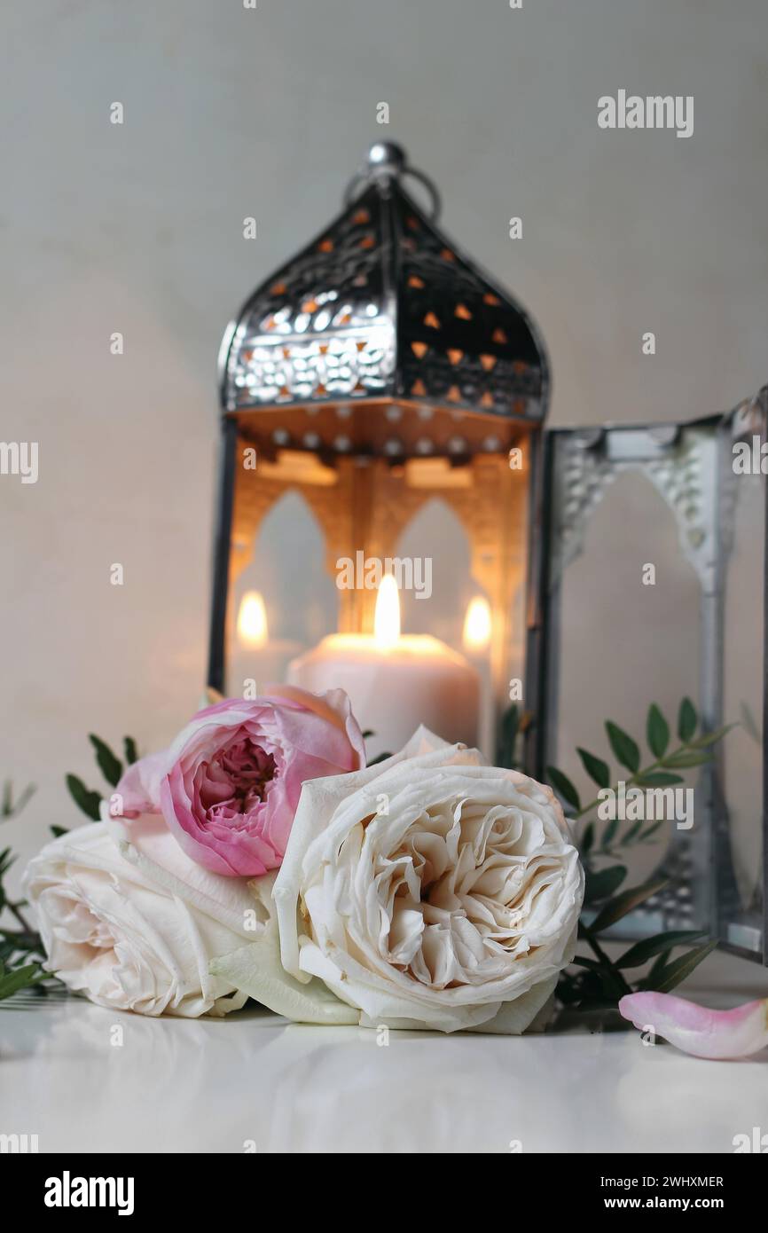 Silver Moroccan, Arabic lantern with burning candle. Pink roses flowers ...