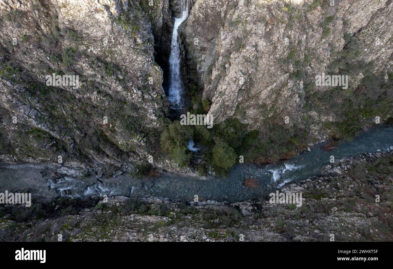 Drone aerial of waterfall flowing from a rocky cliff in the gorge ...