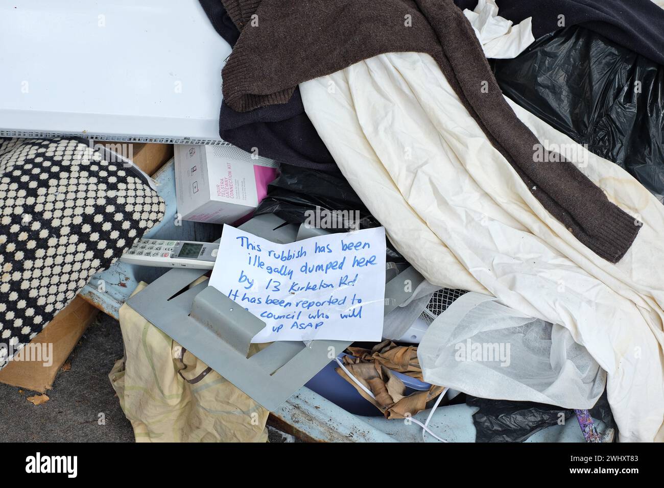 Handwritten note on a pile of personal goods dumped on the footpath ...