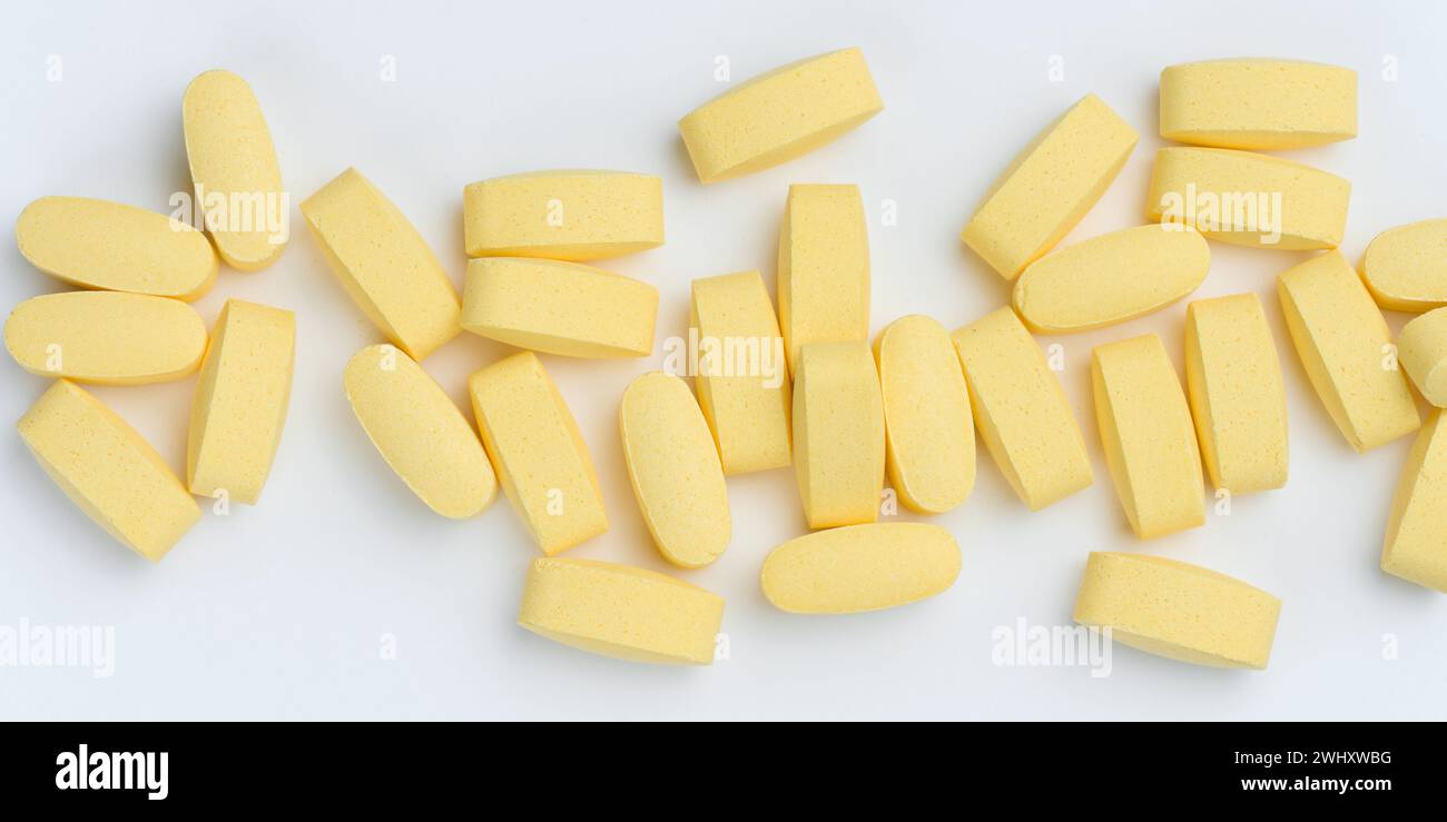 Yellow oval tablets on a white background, top view Stock Photo - Alamy