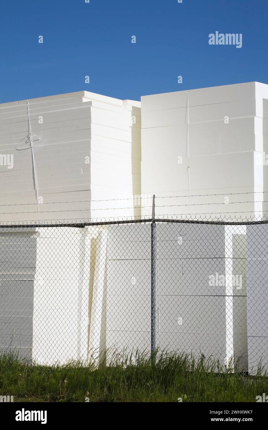 Stacks of white styrofoam panels behind wire mesh security fence in ...