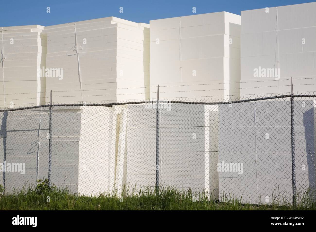 Stacks of white styrofoam panels behind wire mesh security fence in ...
