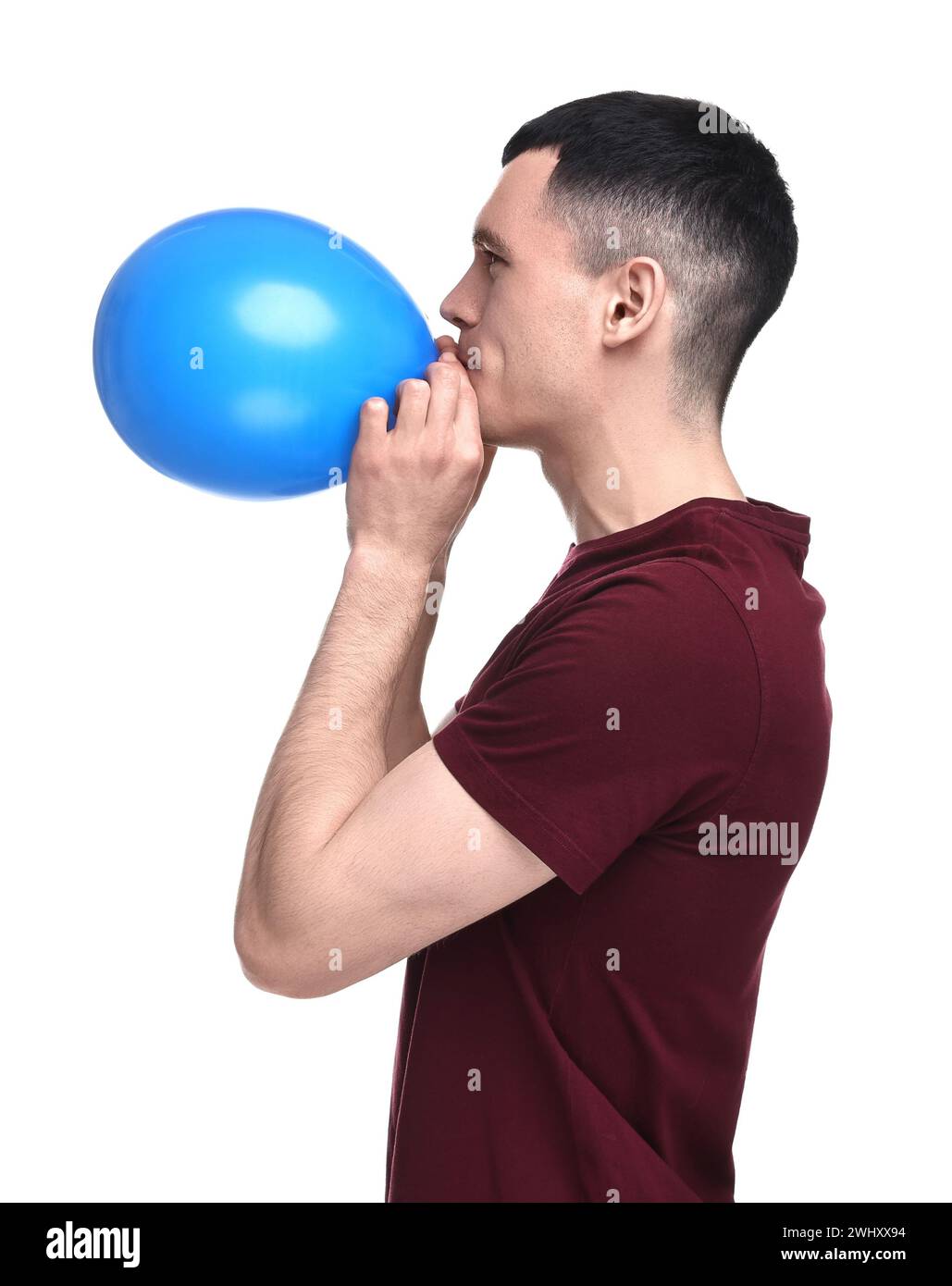 Young man inflating light blue balloon on white background Stock Photo ...