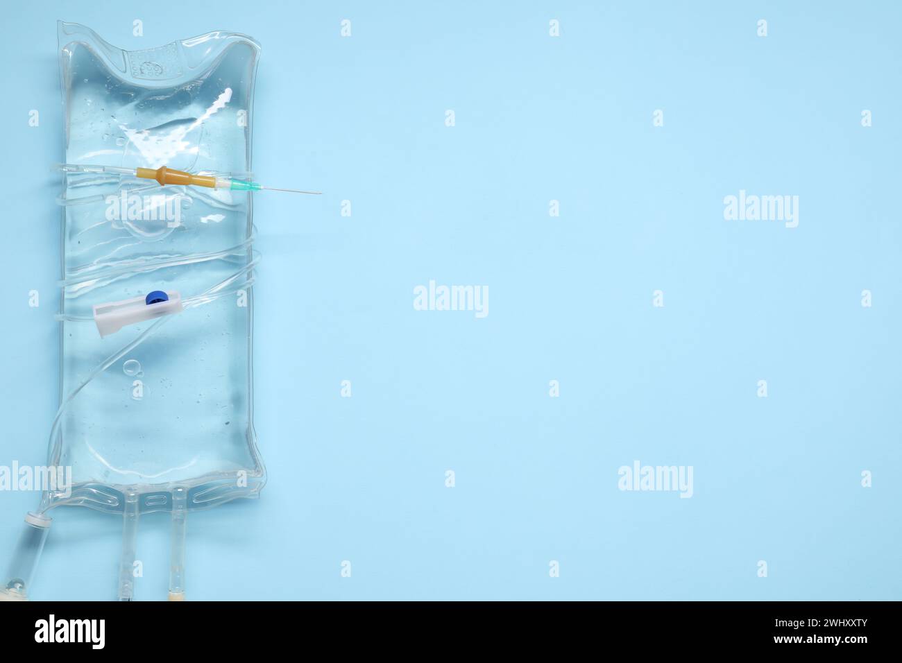IV infusion set on light blue background, top view. Space for text ...