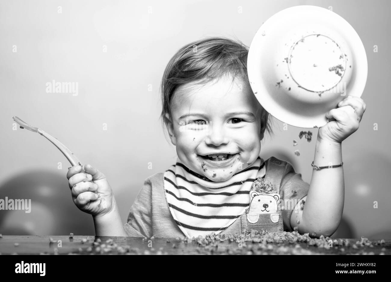 Cute excited funny baby with plate and spoon, babies eating. Kid boy ...