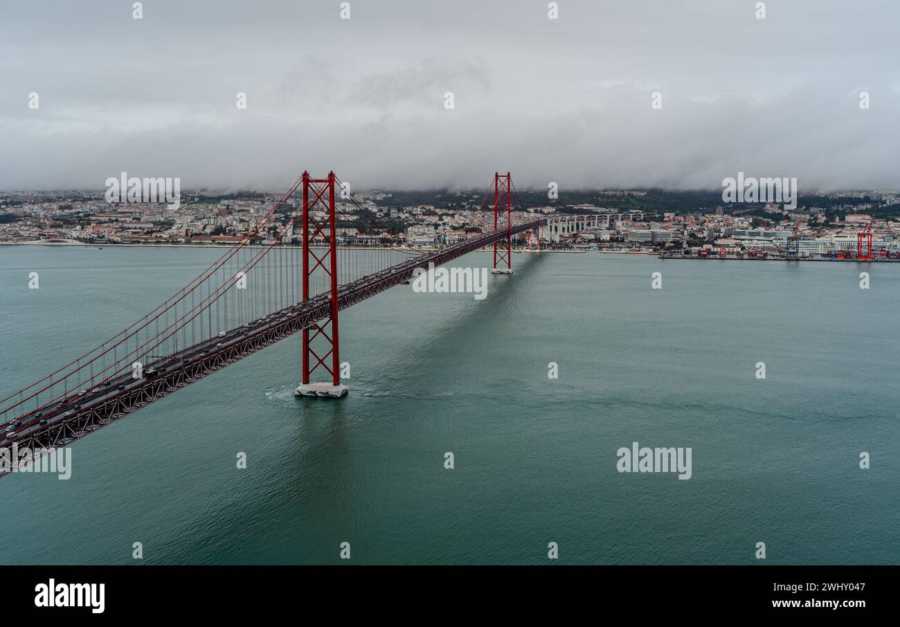 High-angle view of the 25th of April bridge in Lisbon, cloudy sky red ...