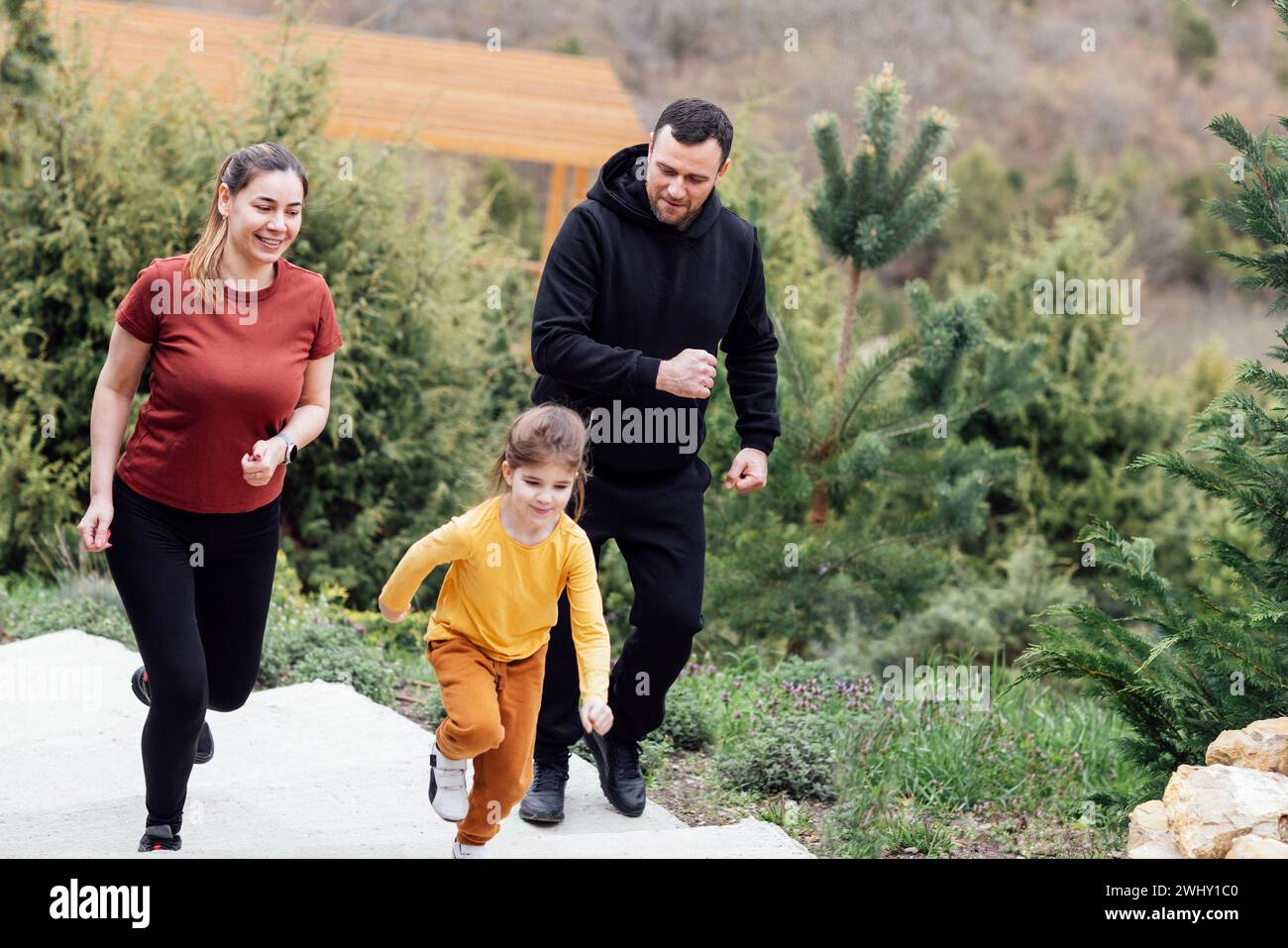 Happy family jogging in the summertime. Smiling young couple with their ...