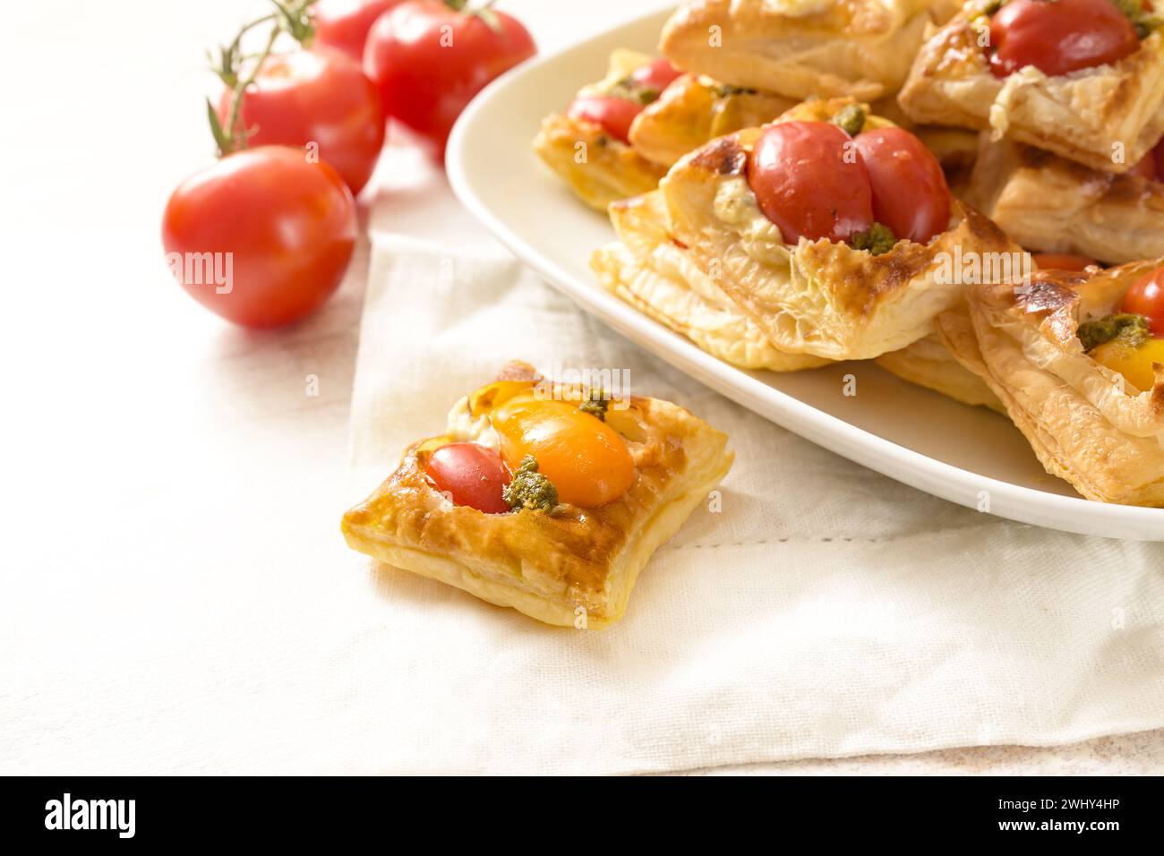 Baked puff pastry snacks with cream cheese, tomatoes and herb pesto ...