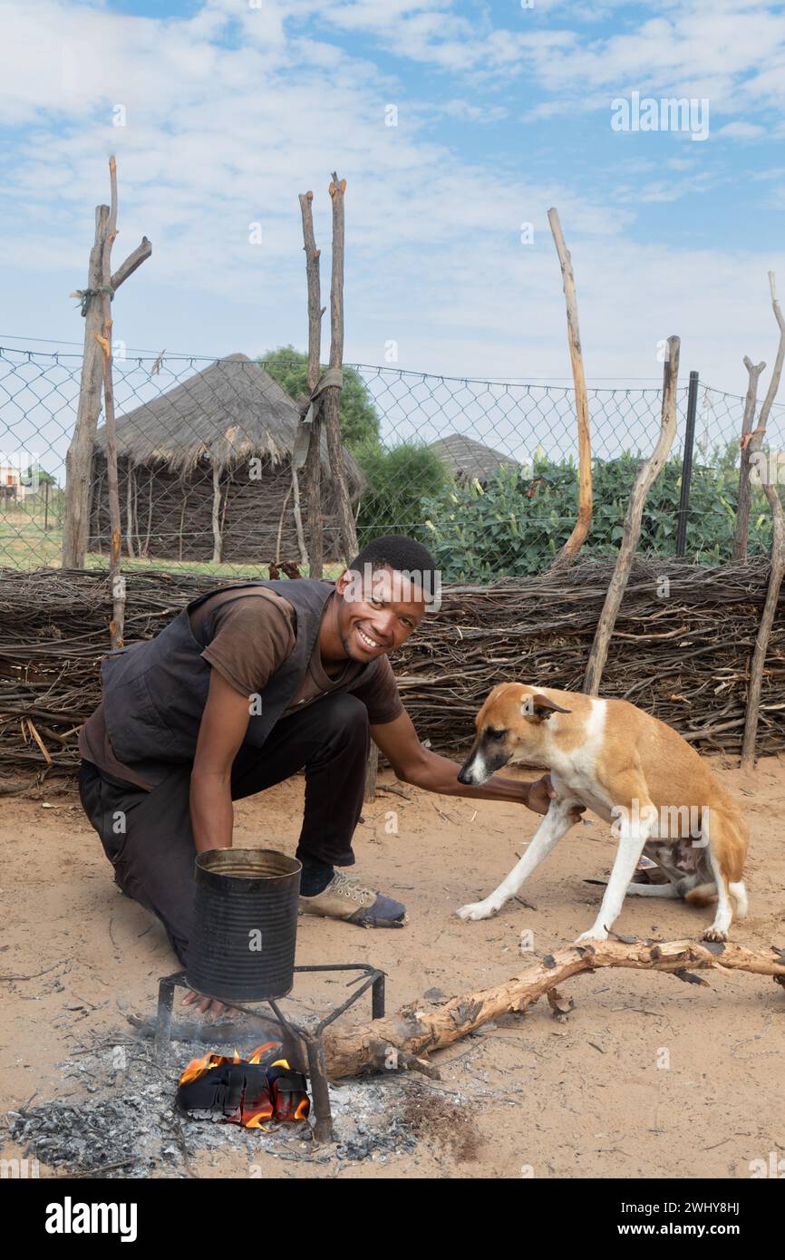 village african man, with his dog in the outdoors kitchen , cooking ...