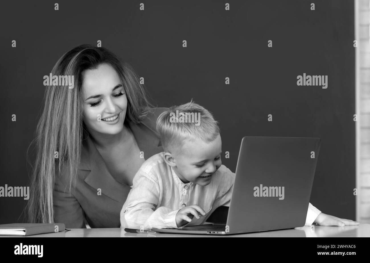 Portrait of schoolkids and teacher talking at school lesson. Mother and son together using ...