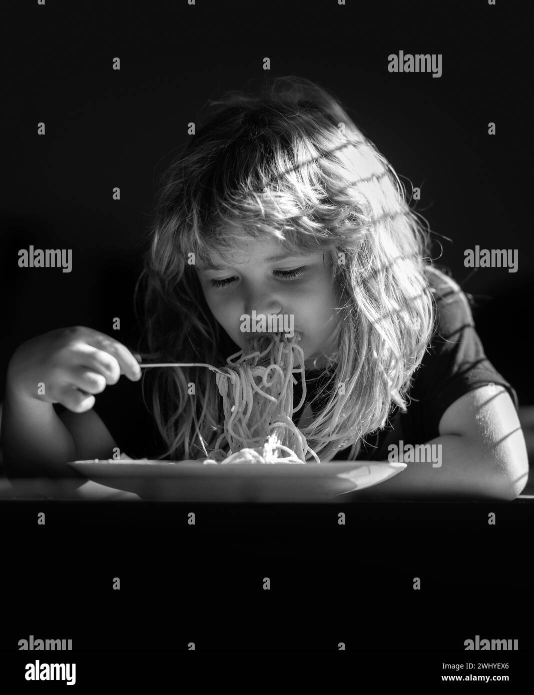 Little kid eating spaghetti in kitchen. Cute child eats food itself ...