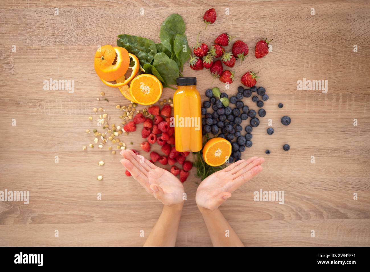 Female hands embracing citrus fruits, berries, greens, sprouted beans ...