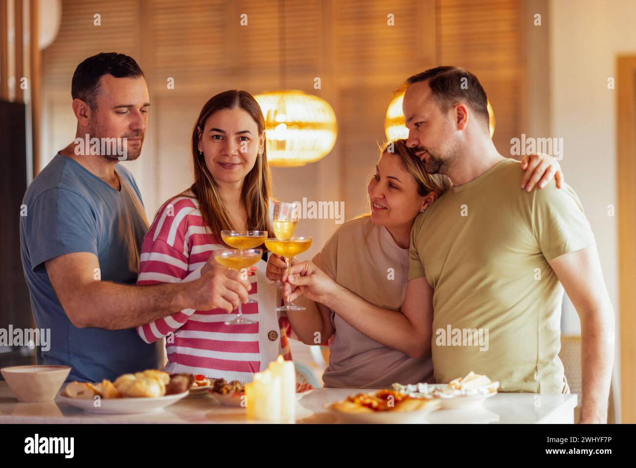 Two married couples hold glasses of champagne and make toast in dining ...