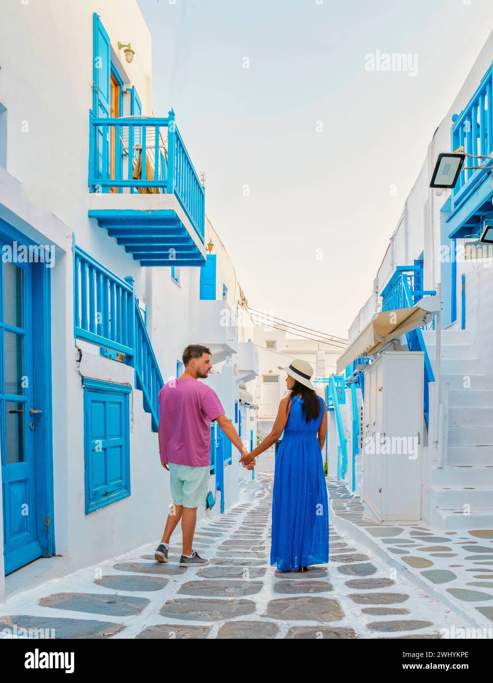 Romantic couple of men and women at the street of Mykonos Greek village ...
