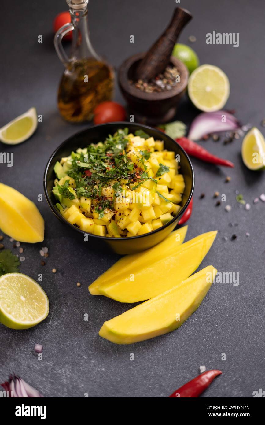 Cooking mango salsa - sliced chopped ingredients in a black ceramic ...