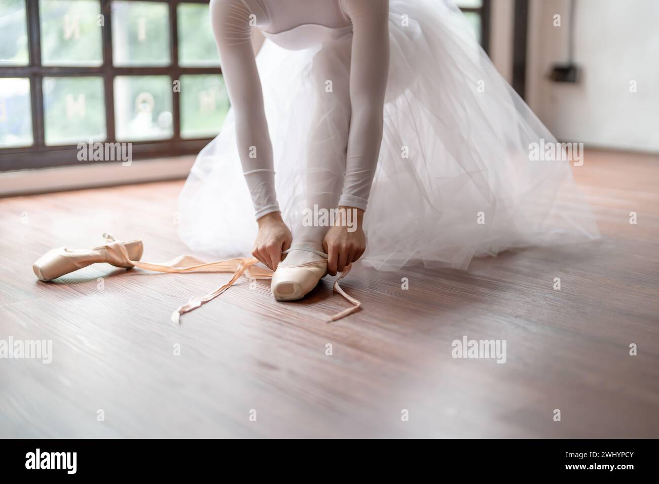 Ballerina in ballet shoes. Asian girlÂ tying ribbons of toe shoes ...