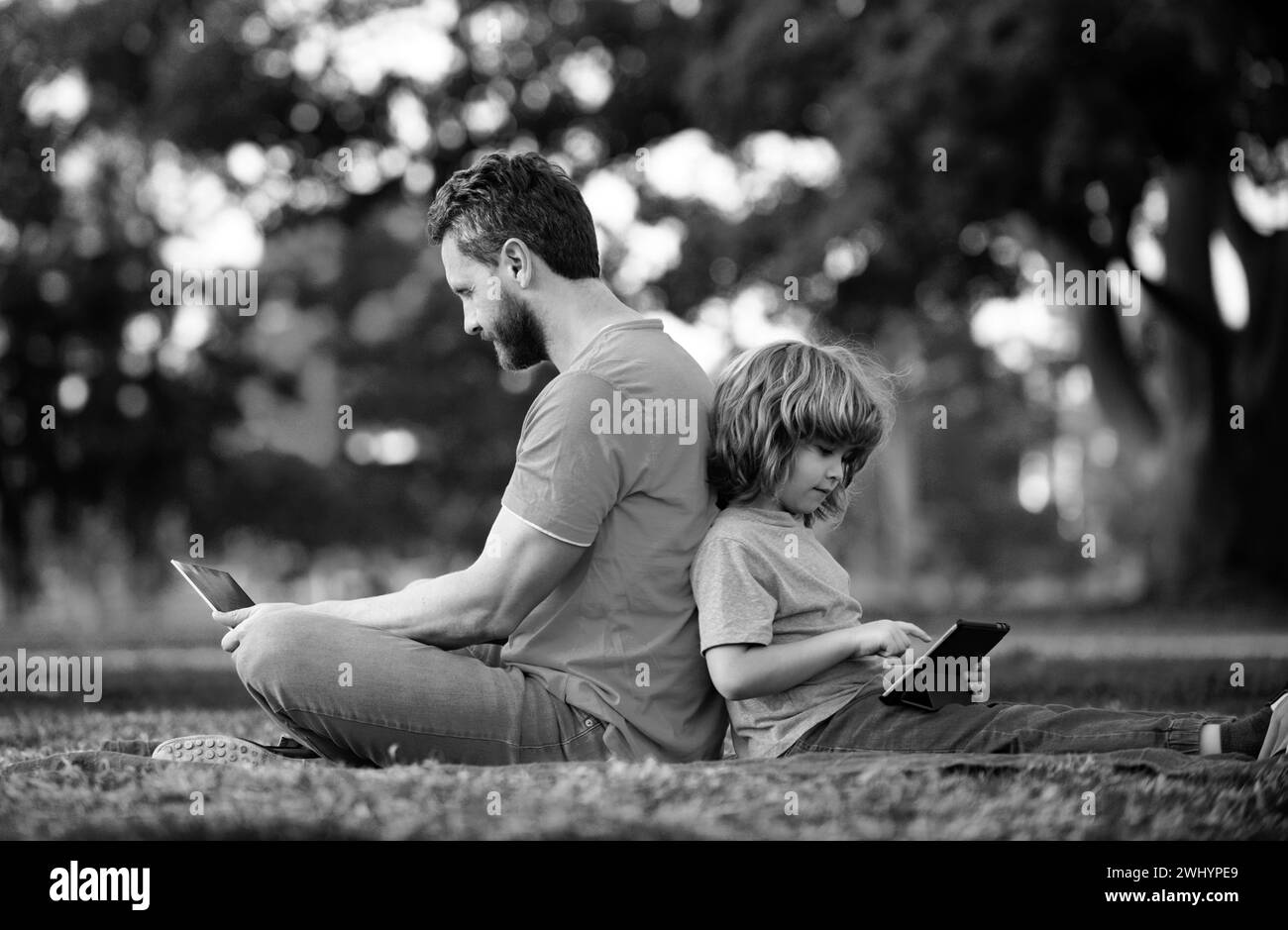 Outdoor distance learning. Father using laptop relax with schooler son ...