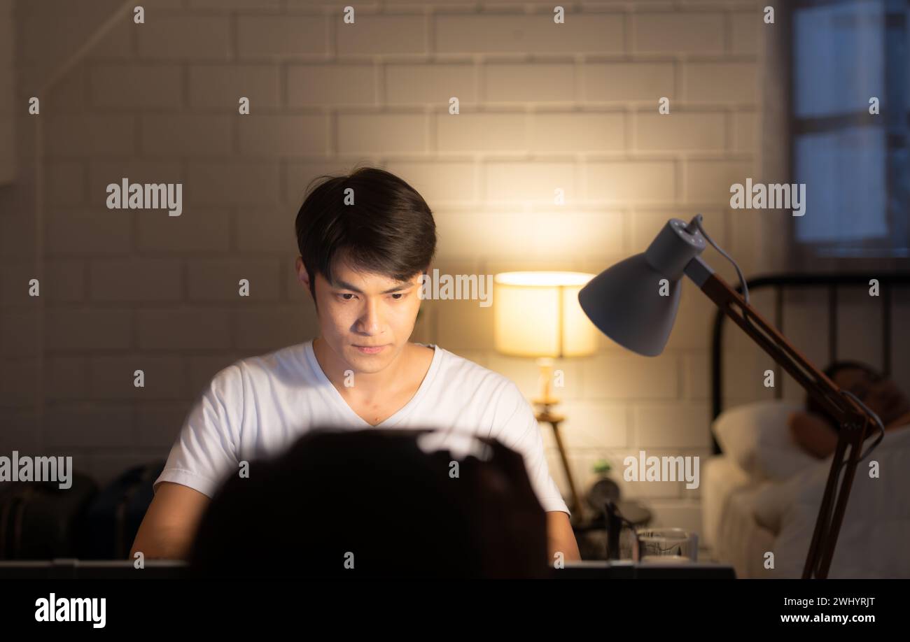 Young attractive and happy Asian man working on laptop computer at home ...