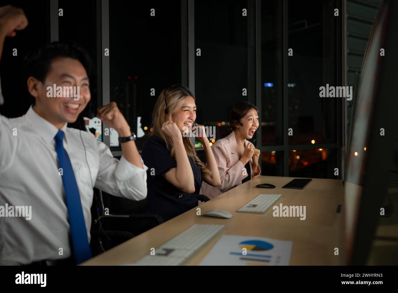 Successful asian business people celebrating success in office at night ...