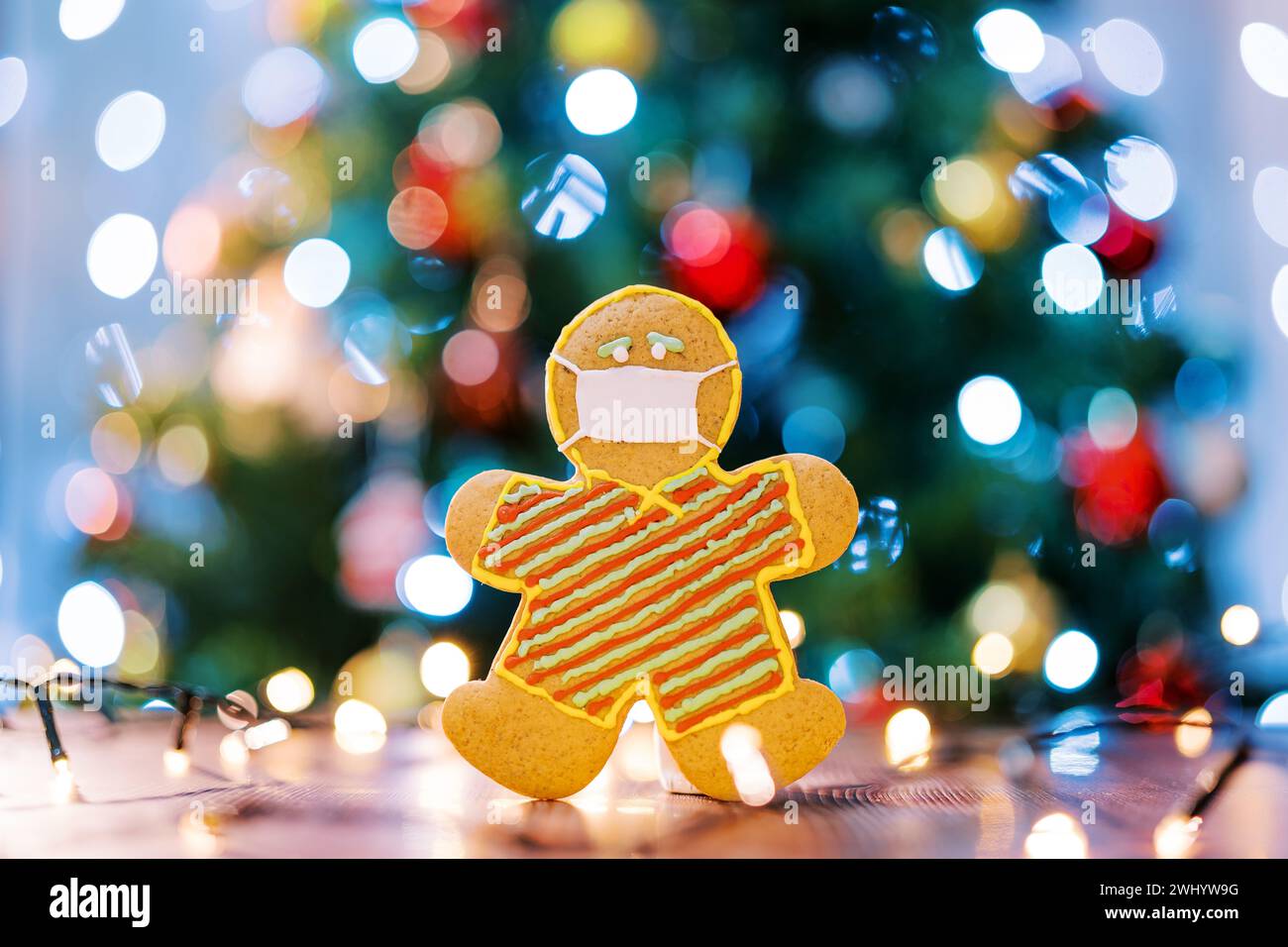Gingerbread man in a protective icing mask on the table in the light of ...