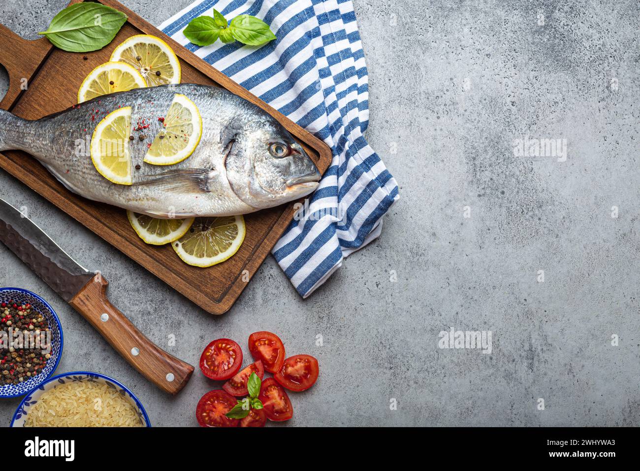 Raw fish dorado with ingredients lemon, fresh basil, cut cherry ...
