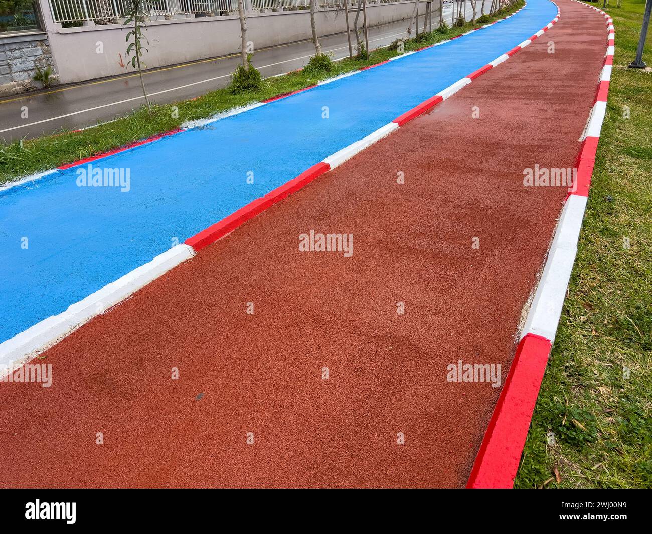 Blue bike path and red running path run side by side through a public ...