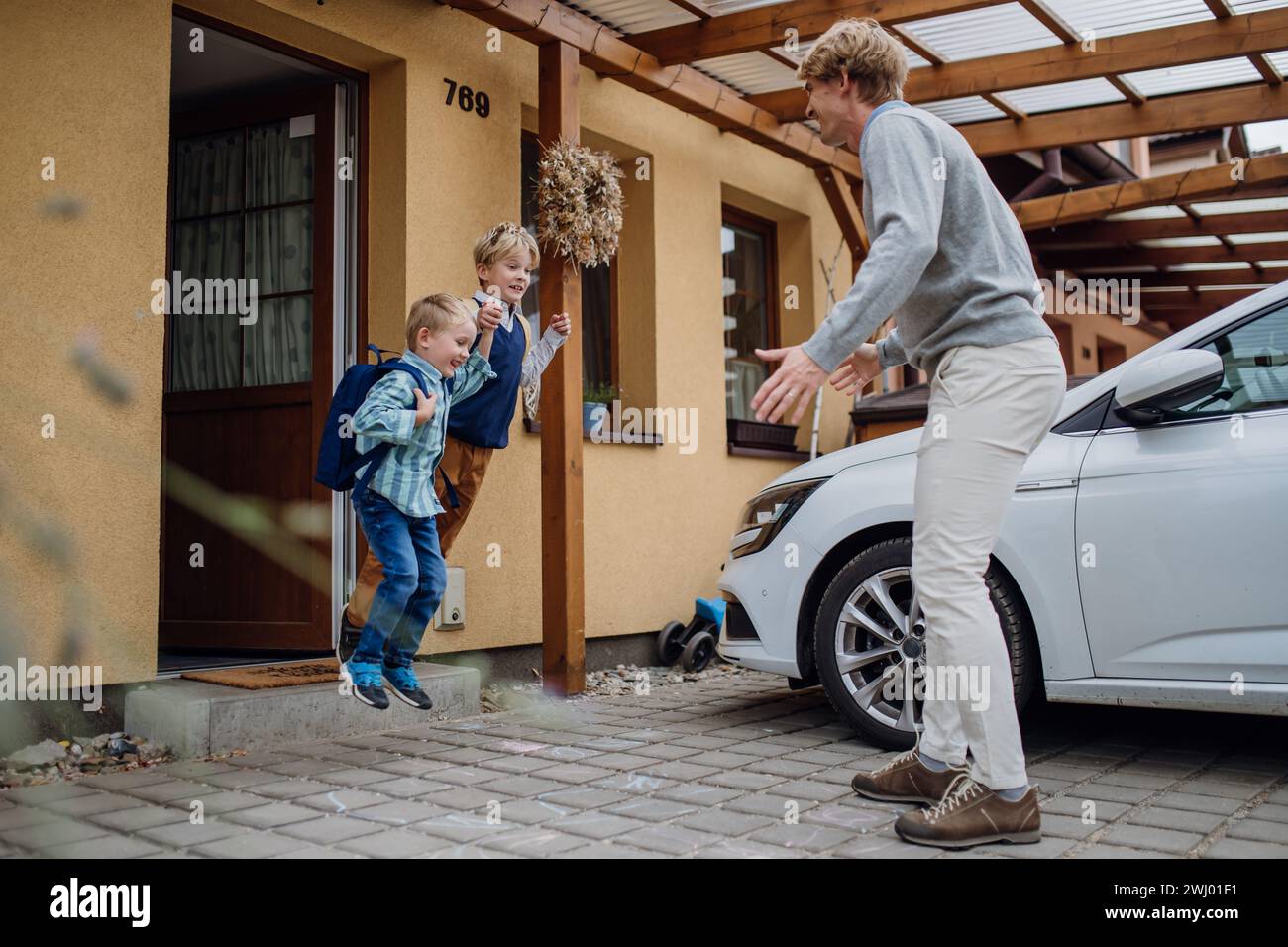 Children getting ready for school, jumping from stair. Father taking ...