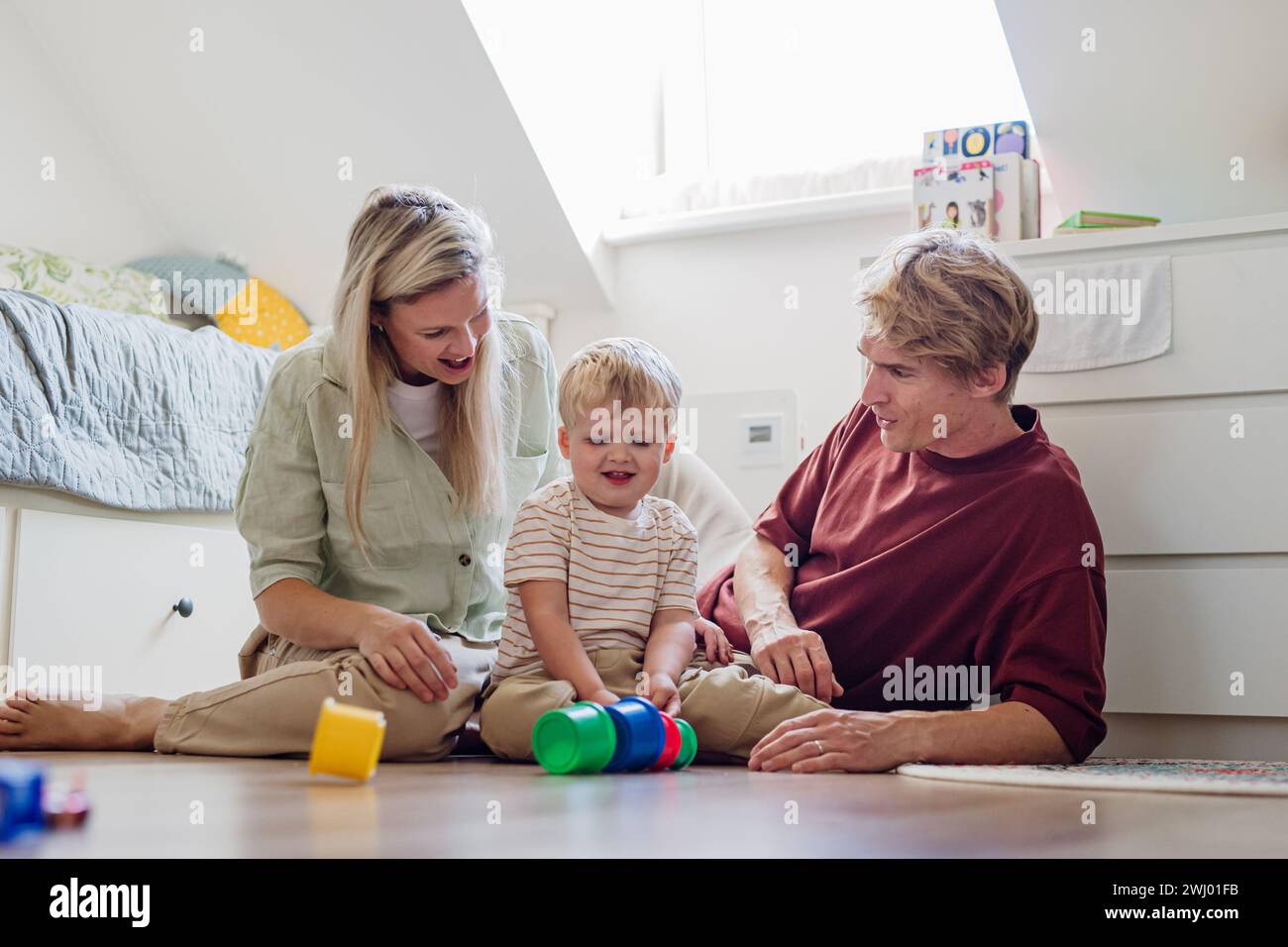 Parents looking at little boy building a tower in childrens room ...