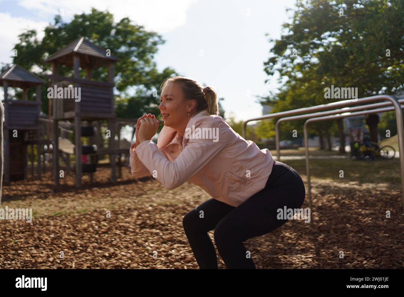 Woman doing squats at an urban outdoor gym. Exercising after work for ...