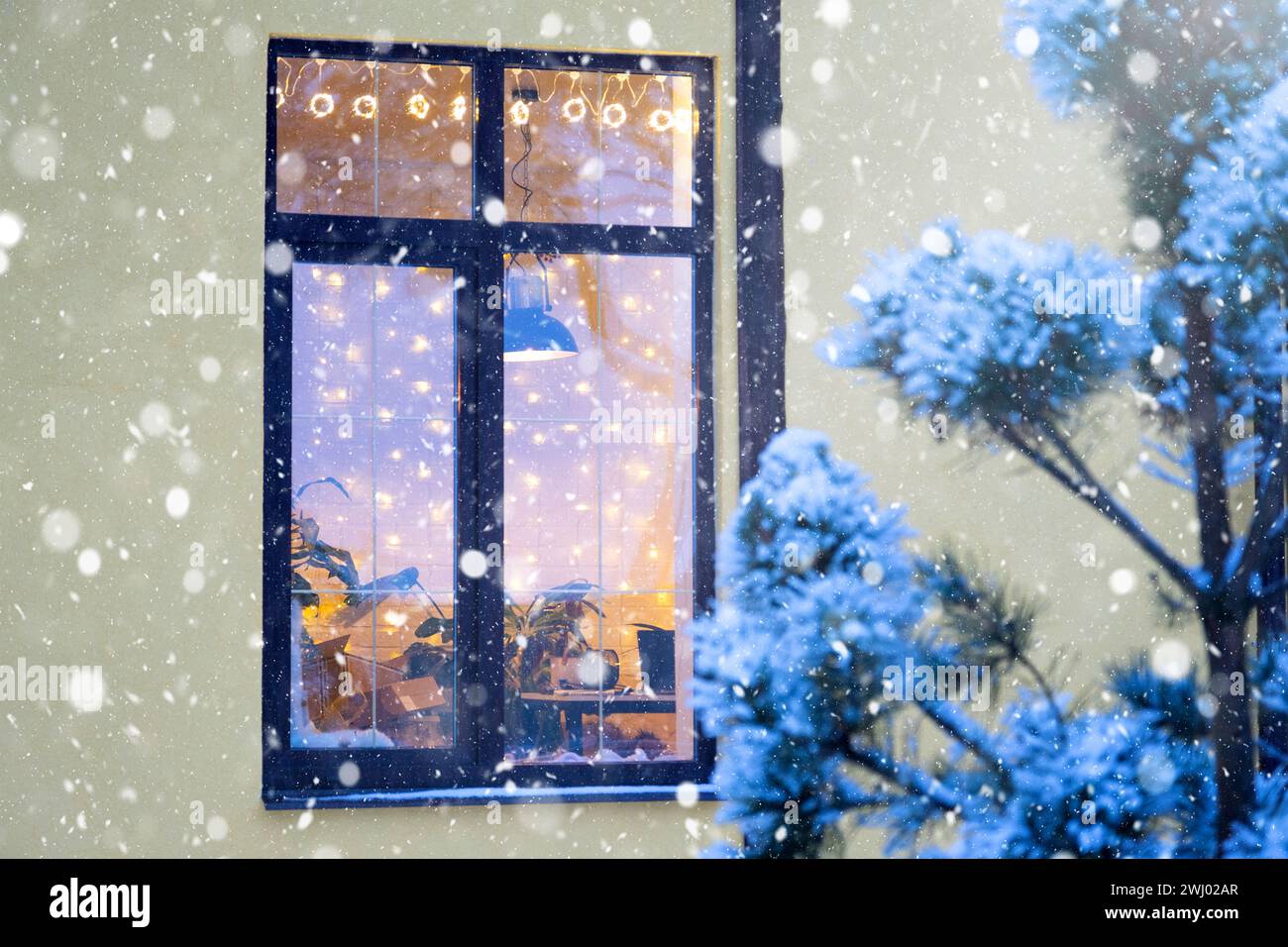 Cozy festive window of the house outside with the warm light of fairy ...