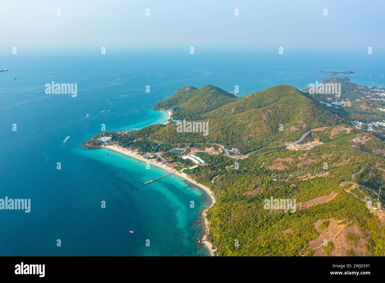 Tropical island with a sandy azure bay and pier and a beach village ...