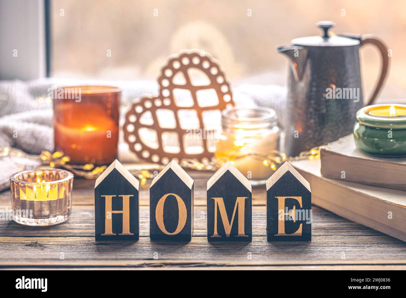 Cozy background with decorative word Home and candles by the window ...