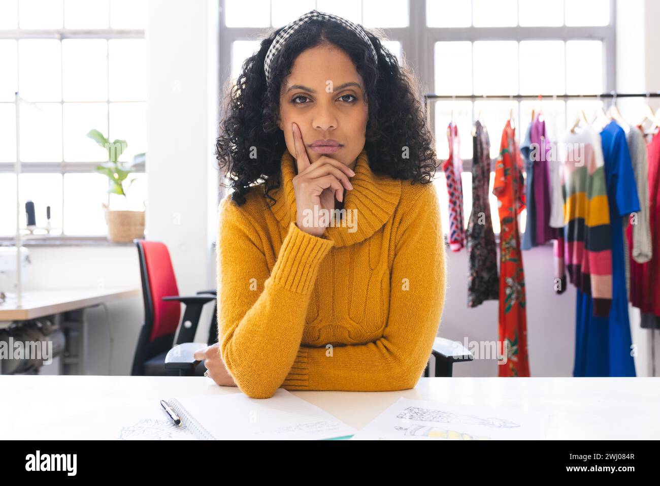 Focused biracial female fashion designer having video call at desk in ...