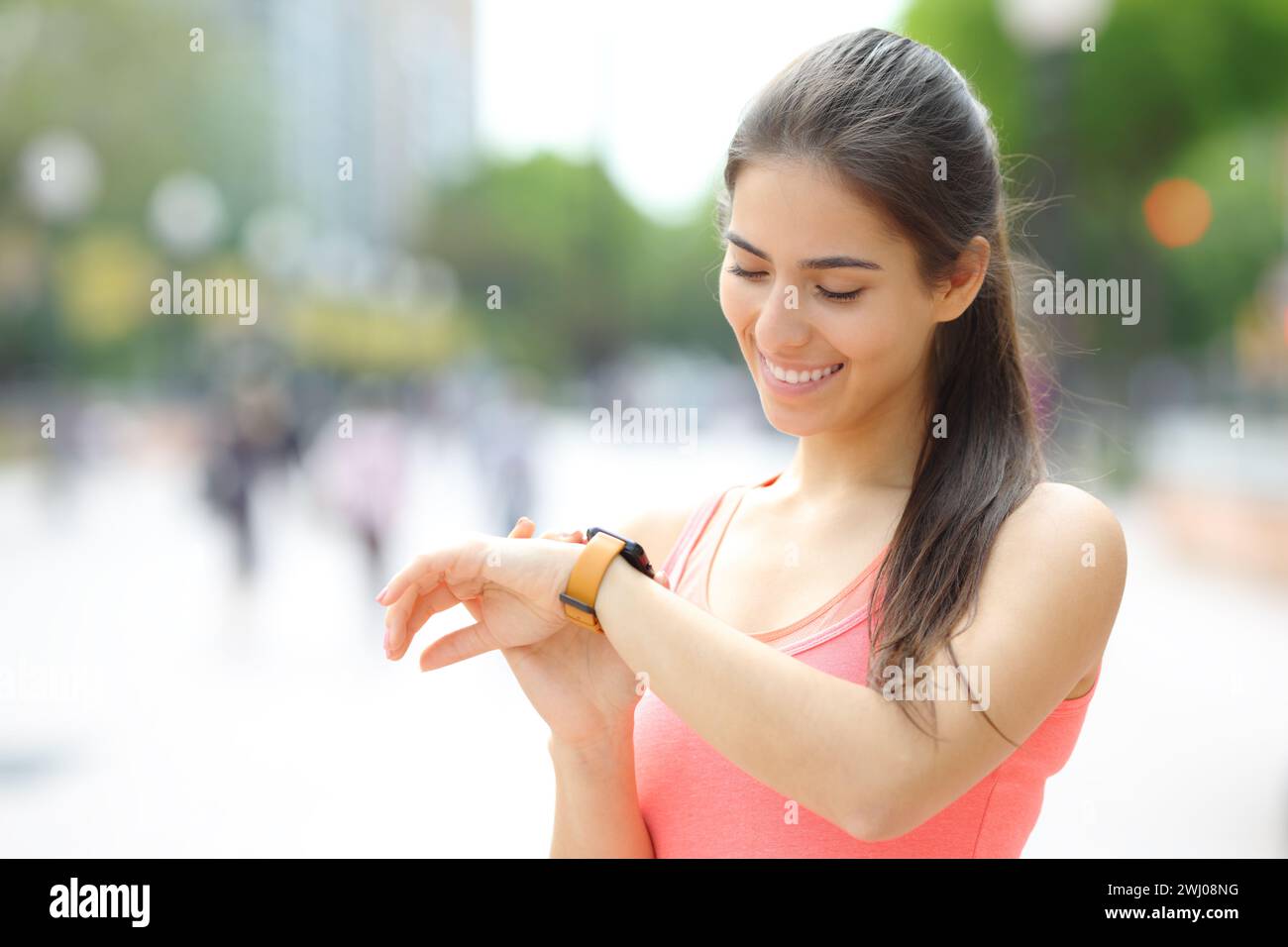 Happy runner checking time on smartwatch after running in the street ...