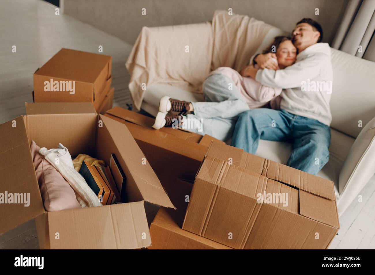 Happy young family couple man and woman relaxing on sofa after moving ...