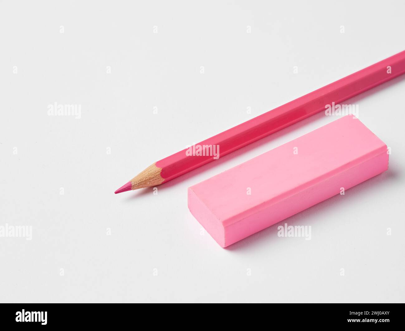 A pink pencil crayon and eraser on white background with copy space ...