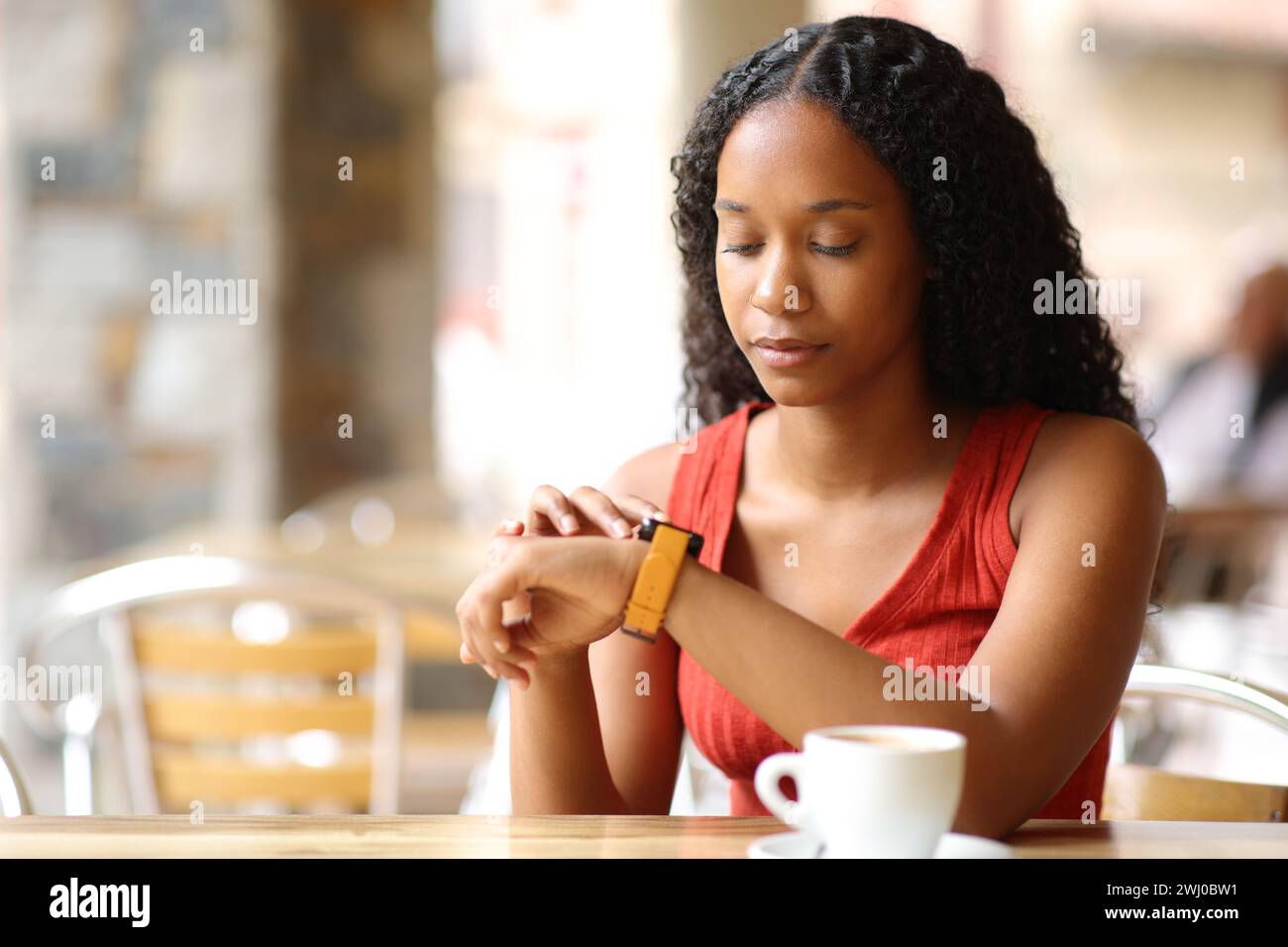 Black serious woman in a restaurant checking smartwatch Stock Photo - Alamy