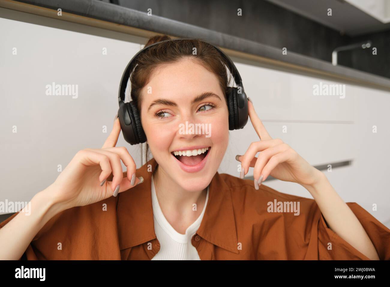 Carefree female model in wireless headphones, listens to music, enjoys ...