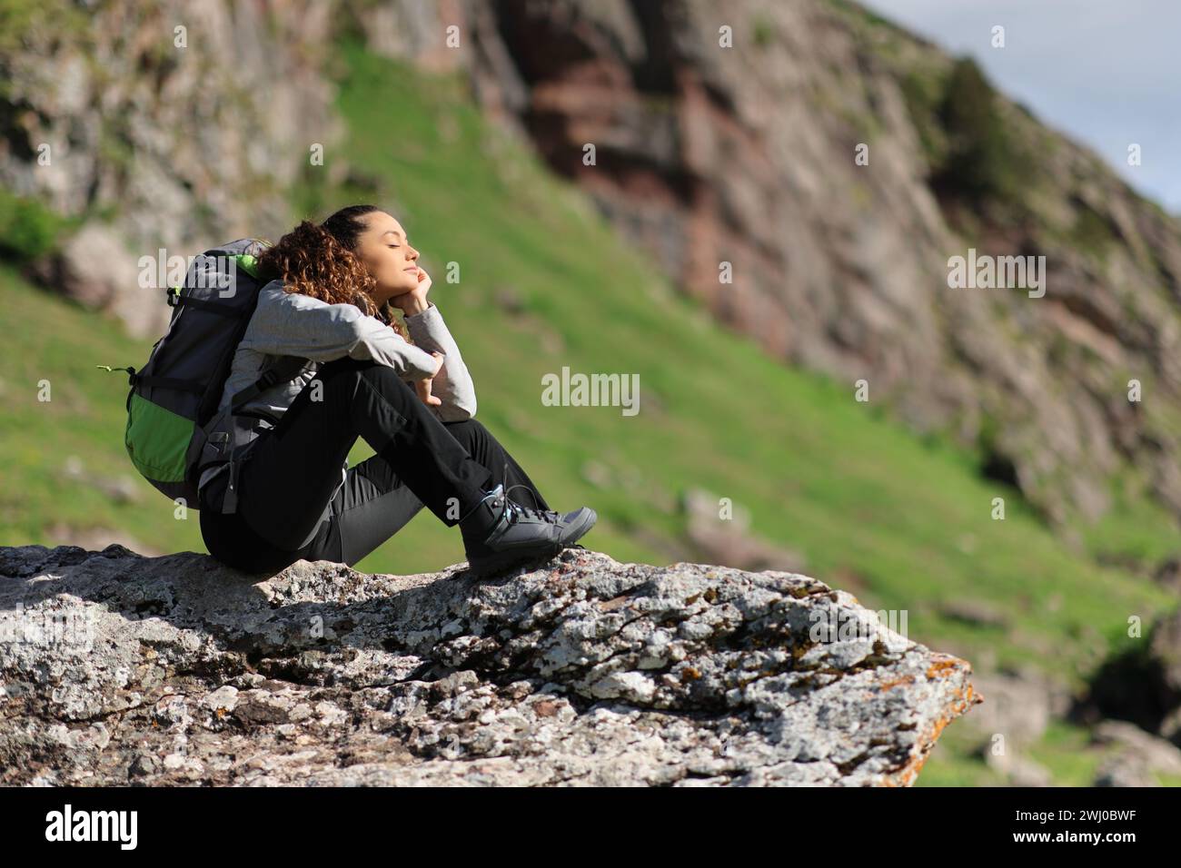 Hiker resting sitting on a rock in the mountain with closed eyes Stock ...