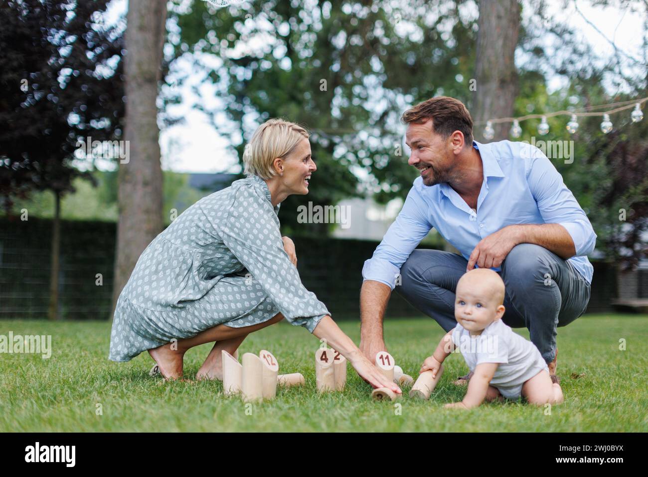 Family with a baby playing in grass at family garden party. Father ...