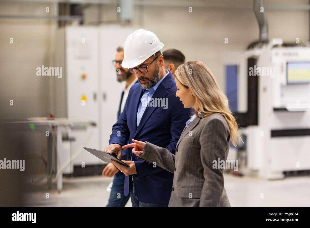 Engineer, foreman consulting with director in modern industrial factory ...