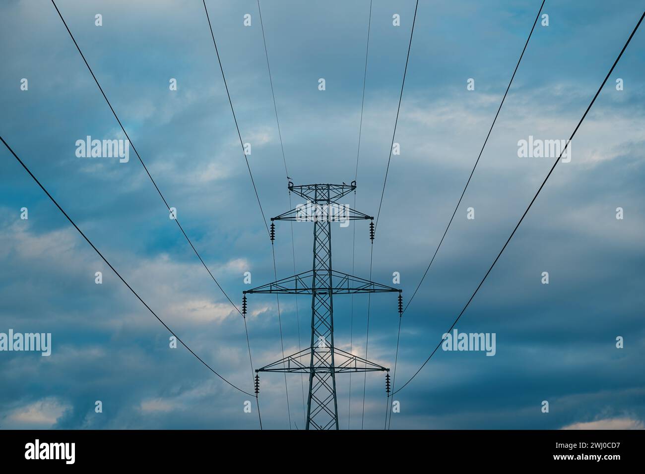 Electricity pylon with overhead powerline cables against cloudy sky ...