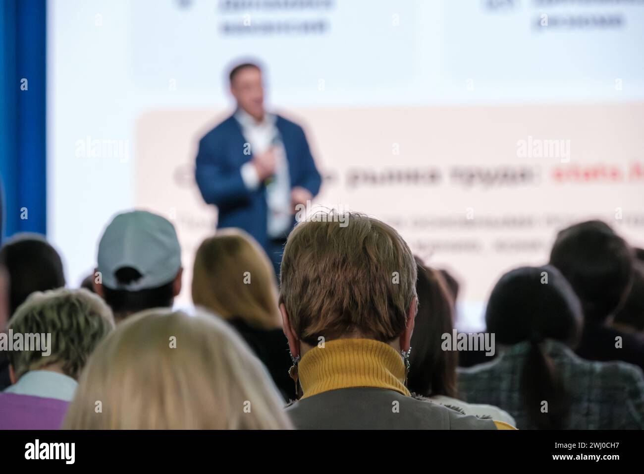 Audience listening to a public speaker at a business event. Focus on ...