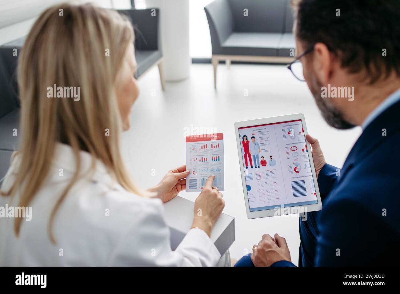 Rear view of pharmaceutical sales representative talking with doctor in ...
