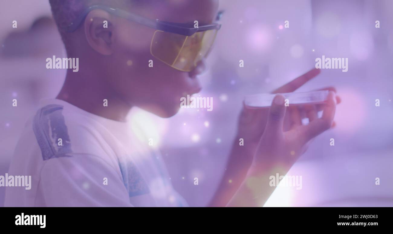 Image of light particles over african american schoolboy studying petri ...